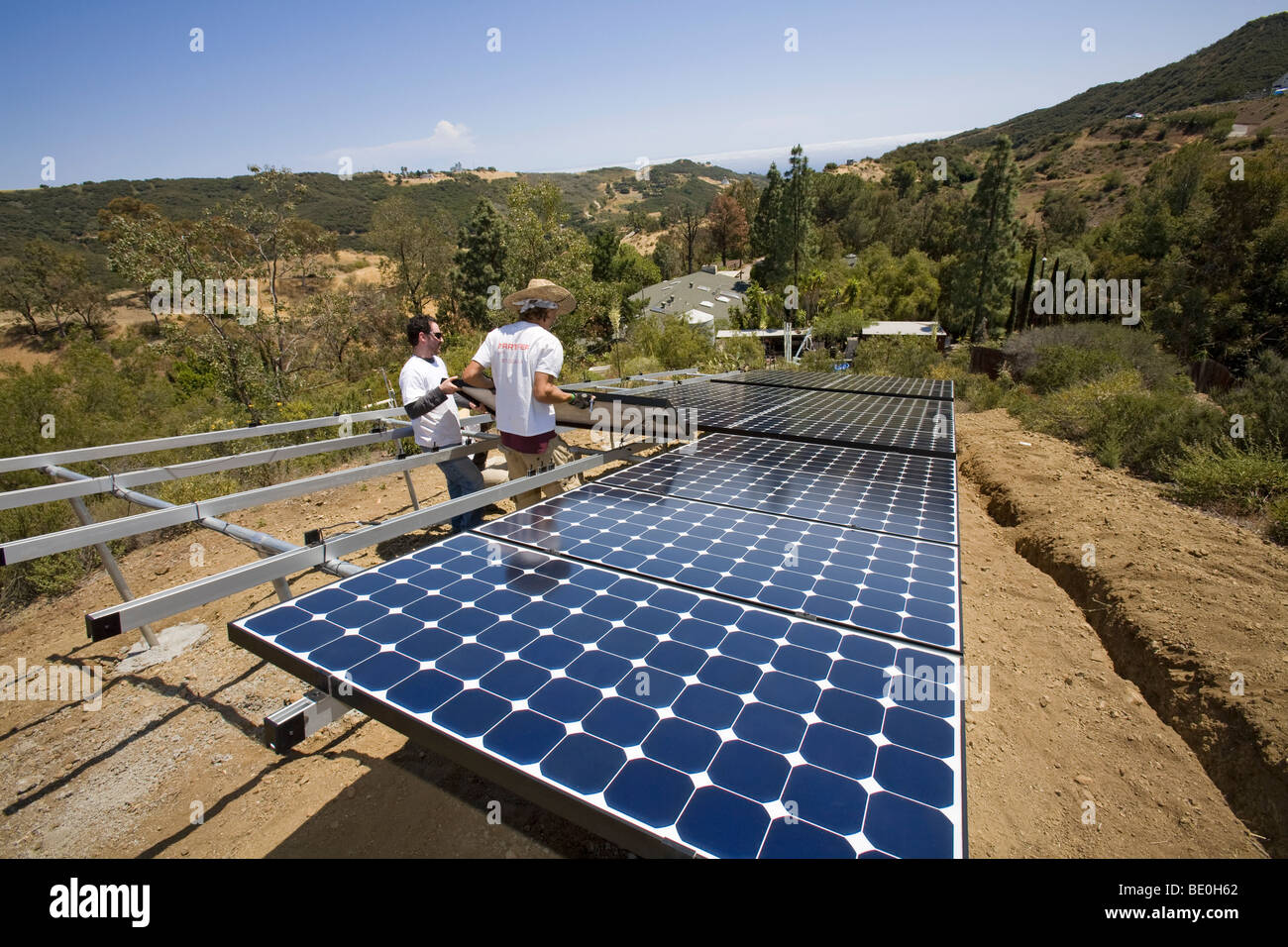 Workers install a solar array on a hillside in Malibu, California, USA ...