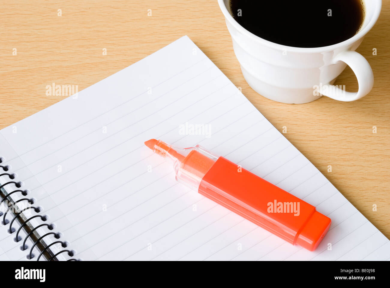 Spiral notebook with cup of coffee and orange highlighter arranged on ...