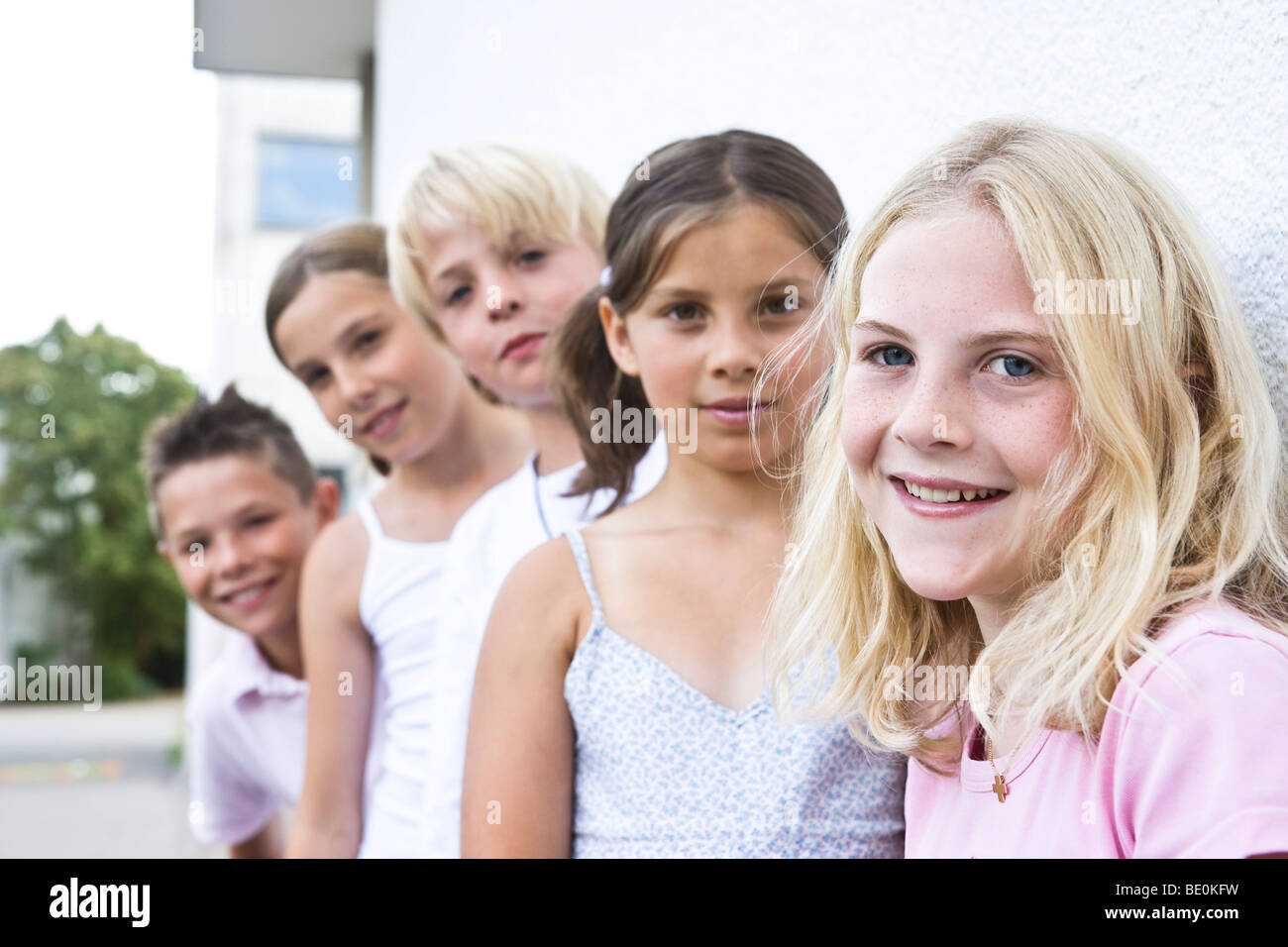 Five friends standing behind each other, in the schoolyard, laughing ...
