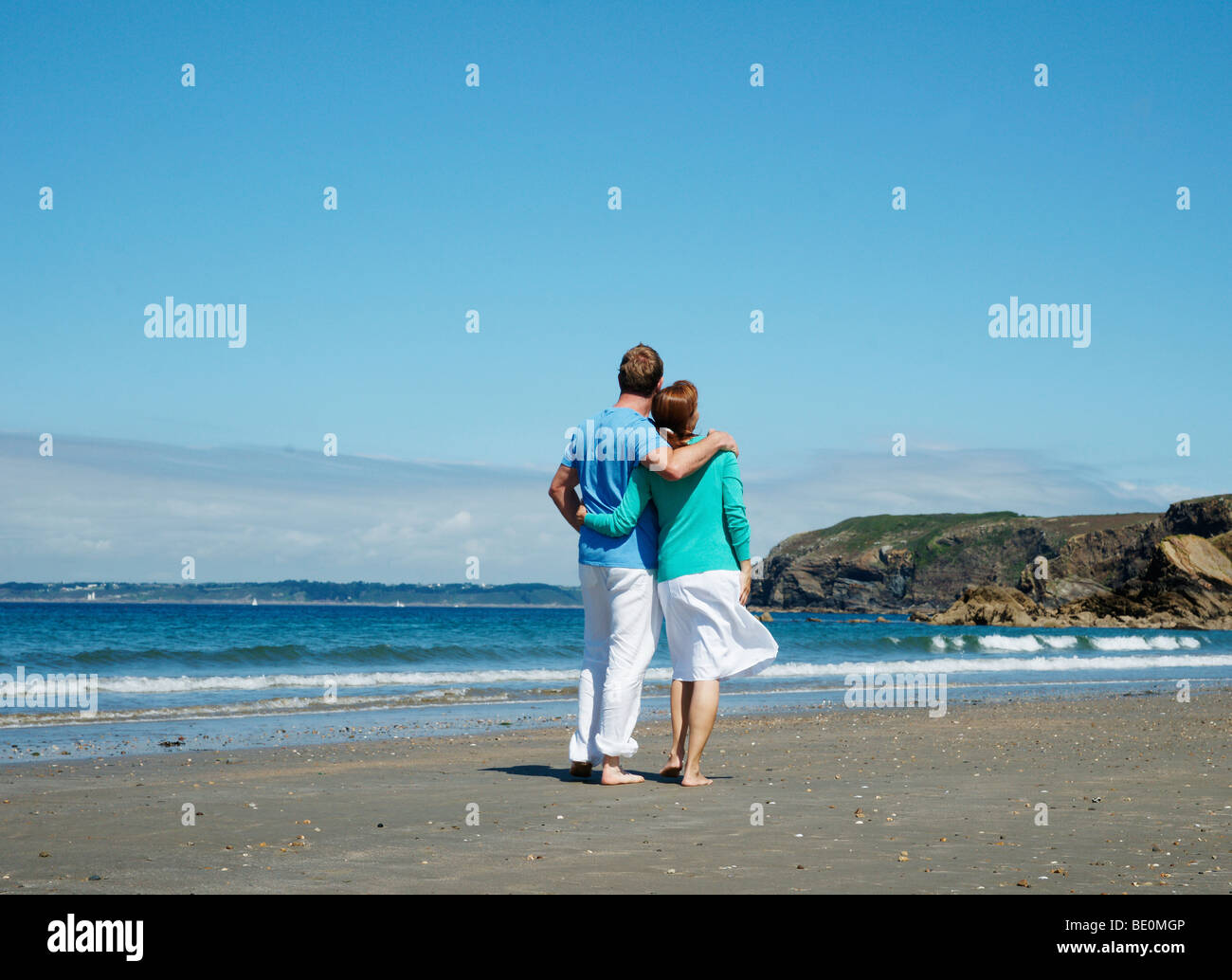 Couple walking arm in arm on the beach Stock Photo - Alamy