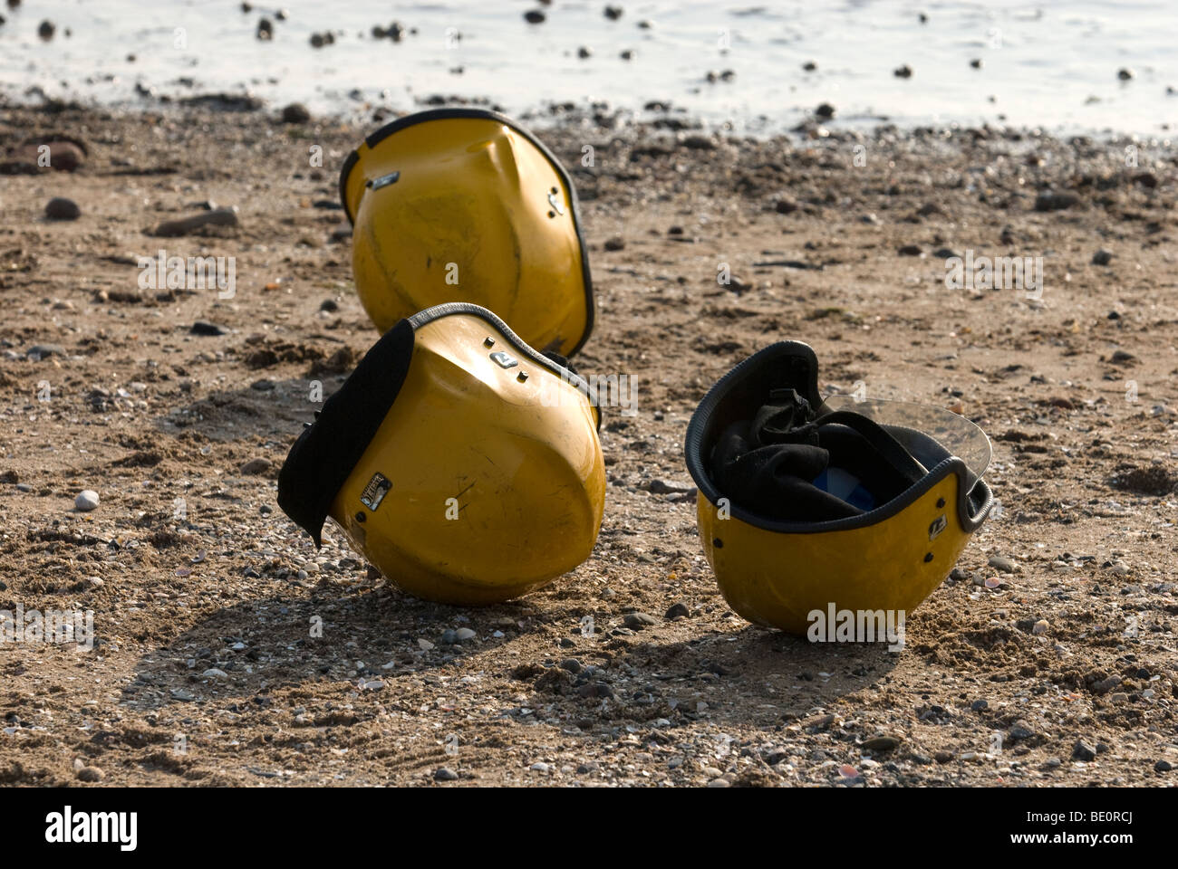 3 fireman's helmets lying in sand on beach Stock Photo - Alamy