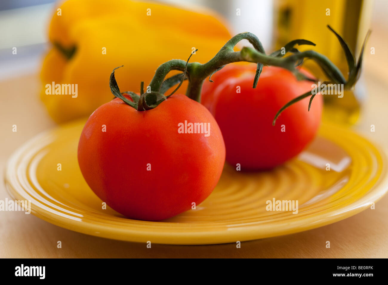 Succulent fresh red tomatoes with attached vine on yellow plate Stock ...