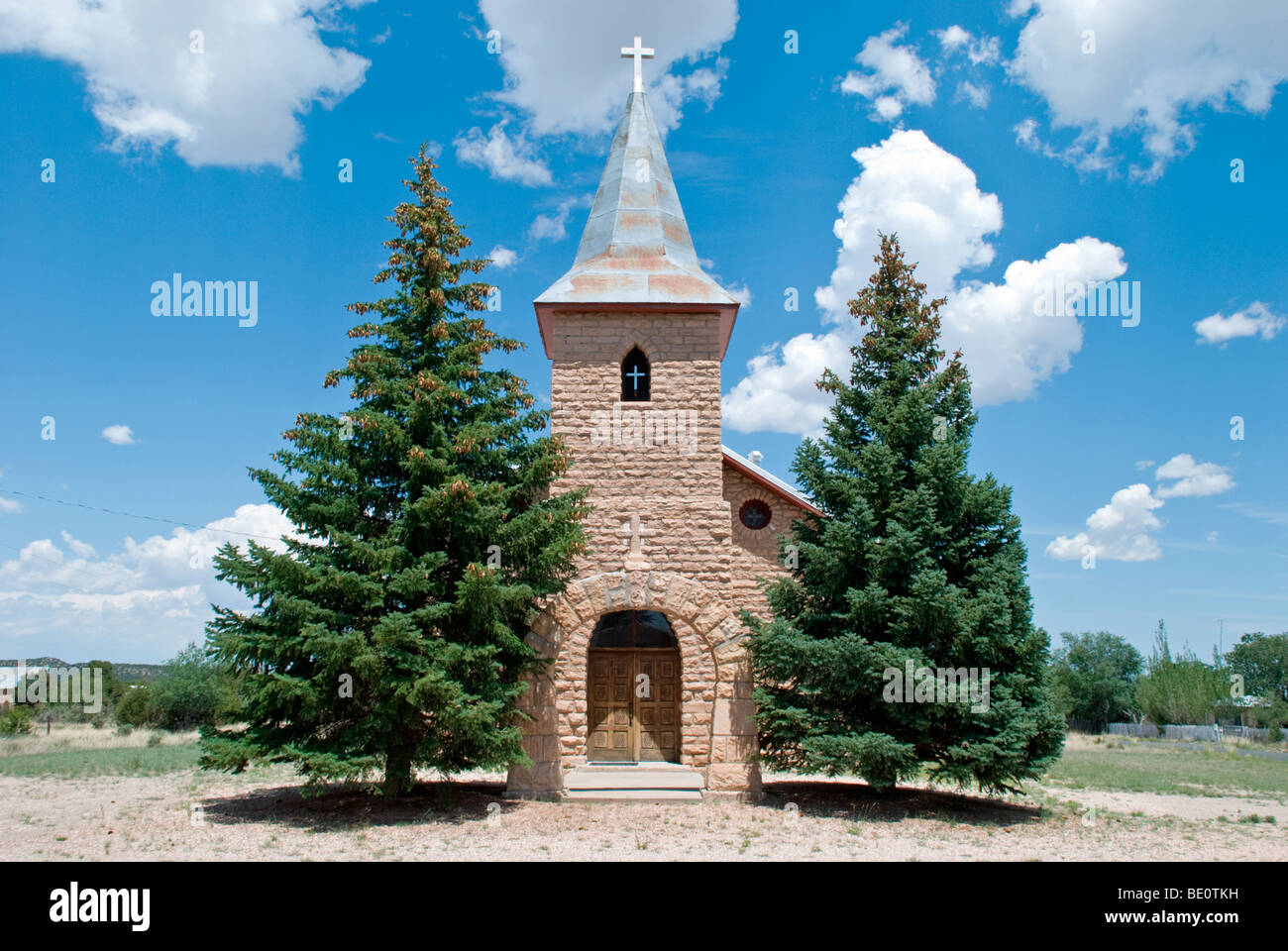 A small stone adobe church sits beneath a beautiful blue sky in the ...