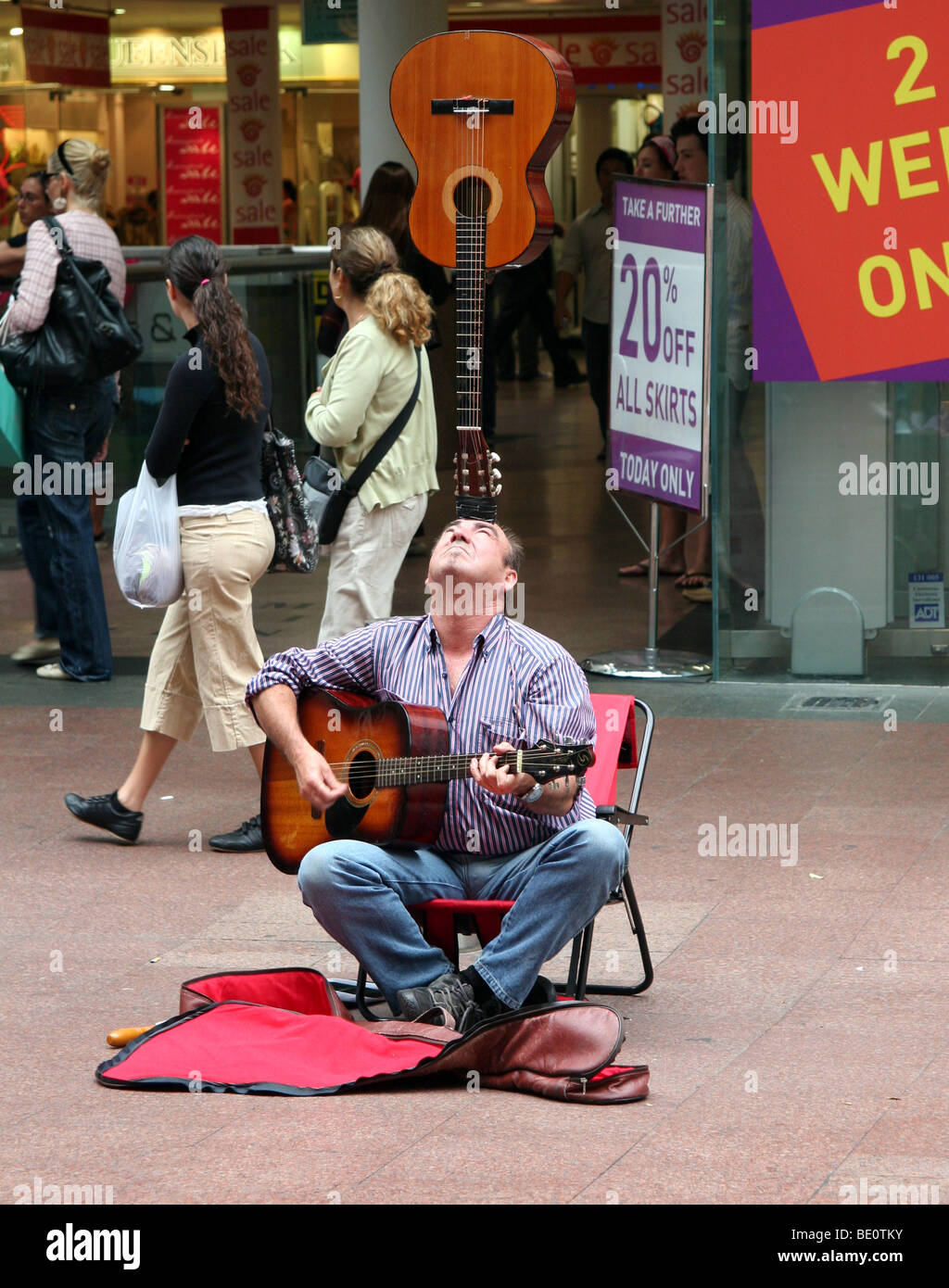 Busker in Sydney playing the guitar with another one balancing on his ...