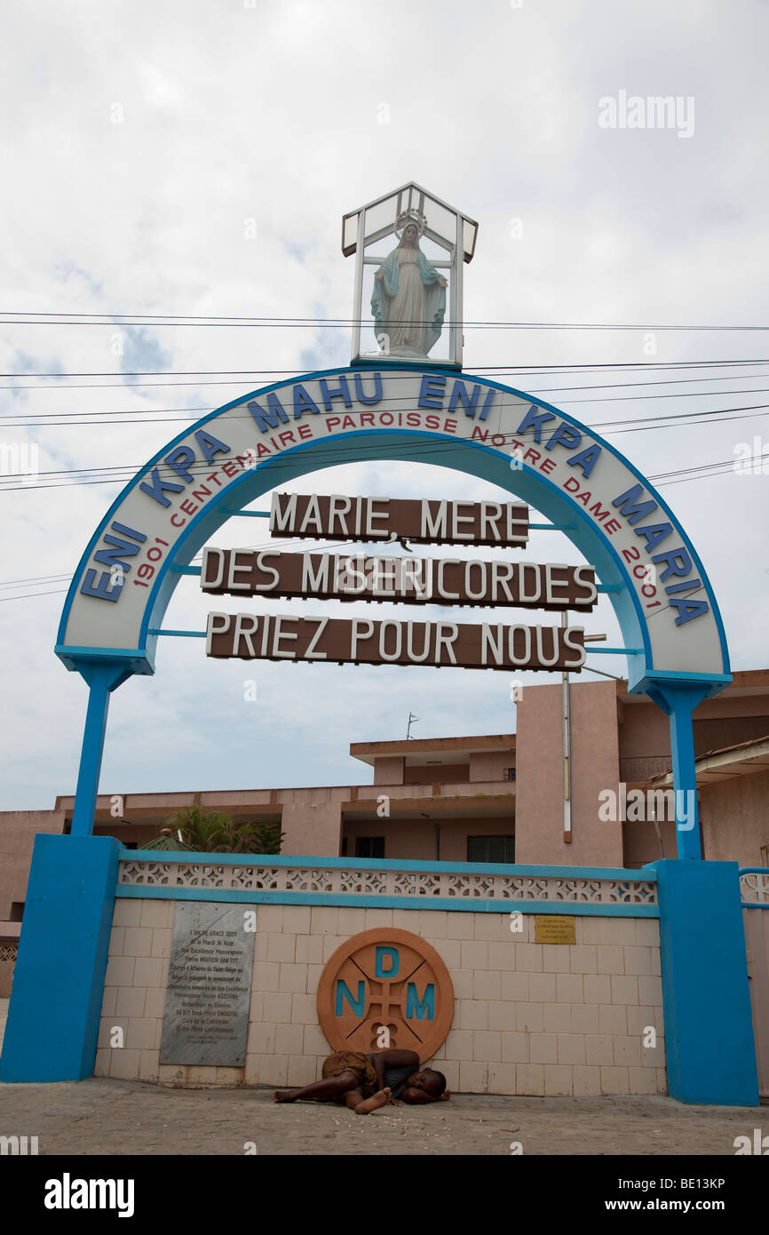 A sick, homeless woman lies on the street outside the walls of the ...