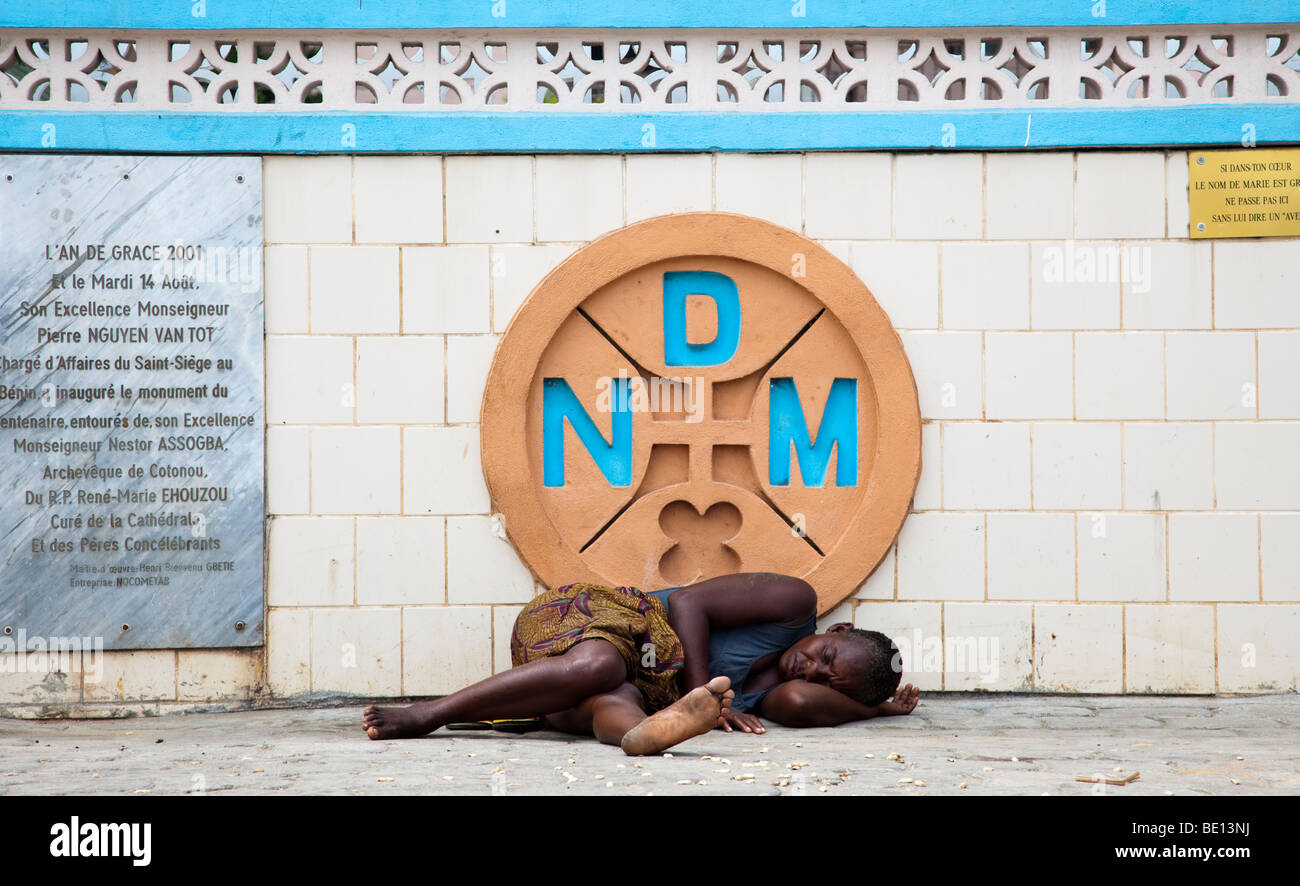 A sick, homeless woman lies on the street outside the walls of the ...