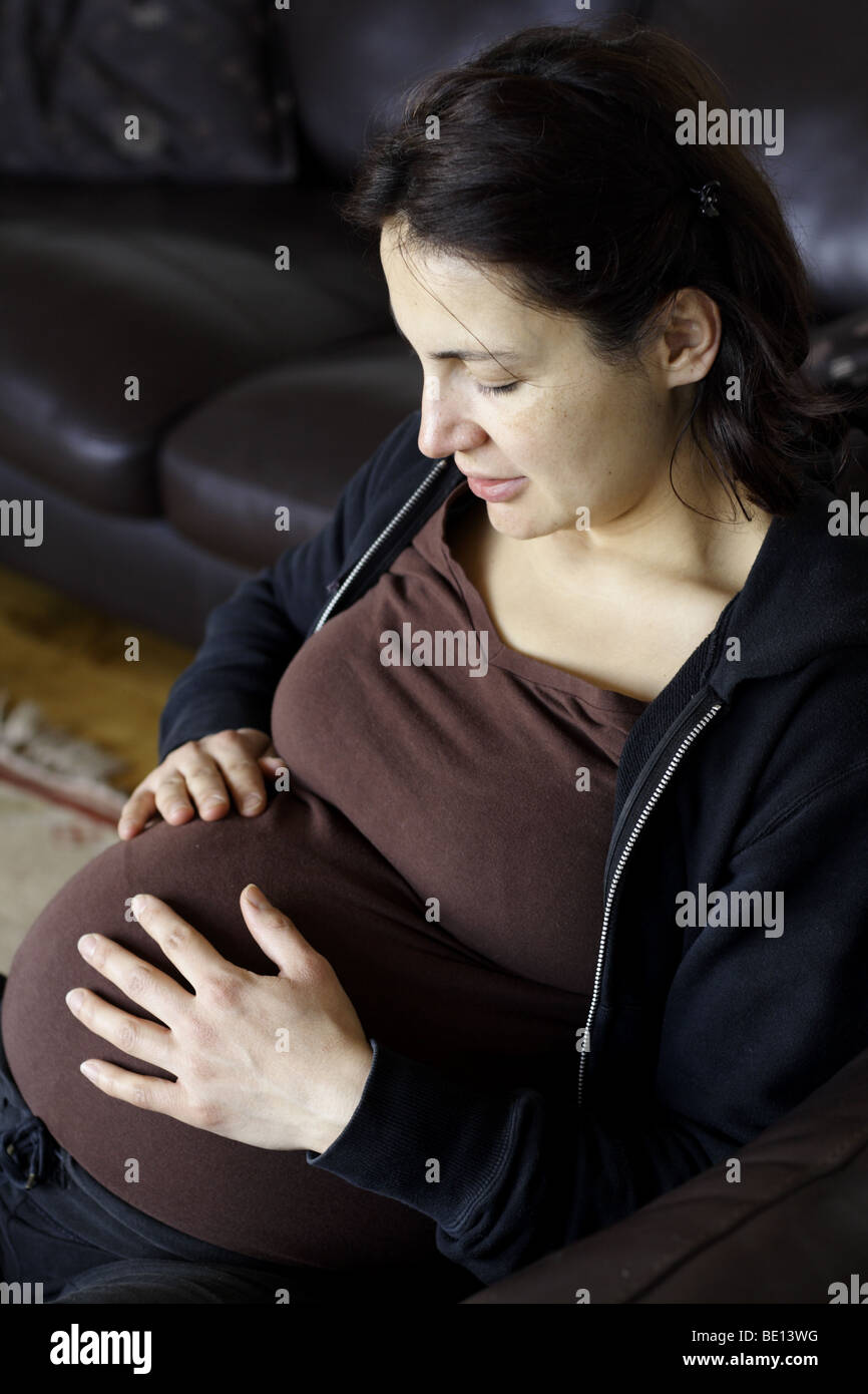 nine month pregnant woman sitting on couch Stock Photo - Alamy