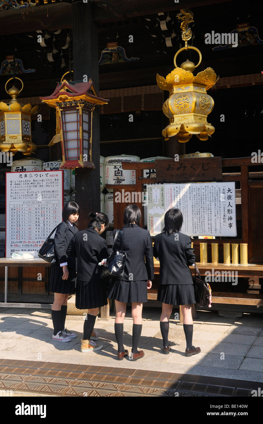Students in uniform praying in front of a Shinto shrine, Kintano Shrine ...