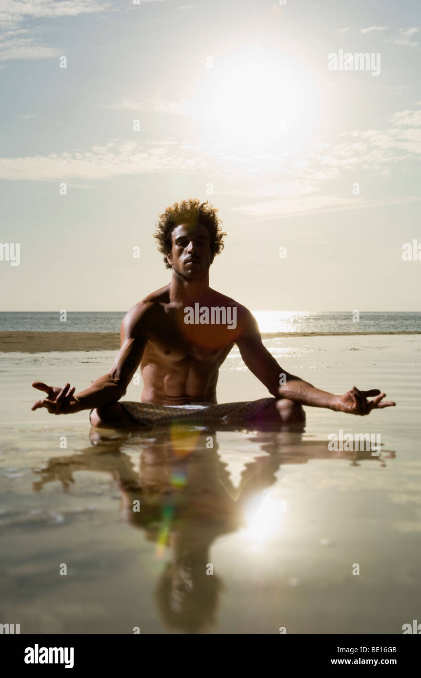 Young man meditating by the seashore Stock Photo - Alamy