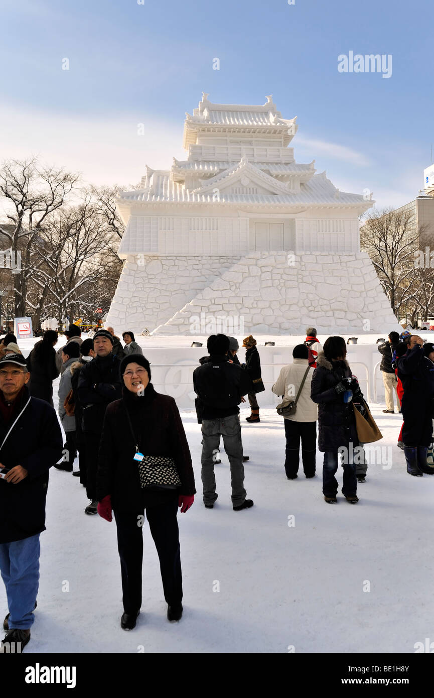 Visitors at the Sapporo Snow Festival with castle made of snow in the ...