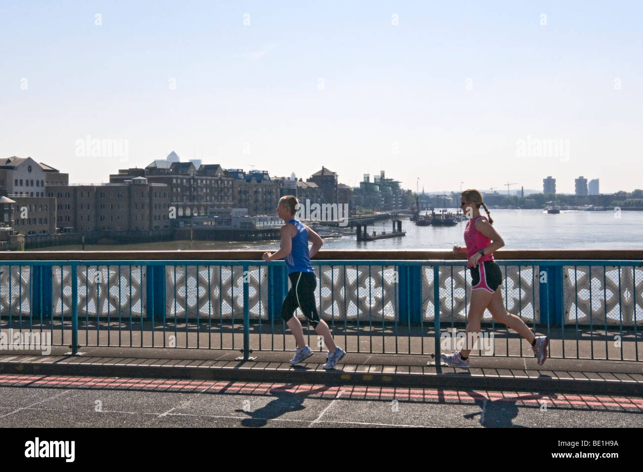 Man and woman running across Tower Bridge, London Stock Photo - Alamy