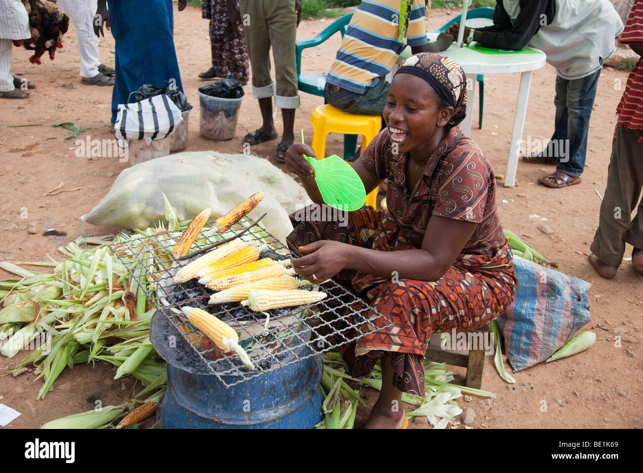 A woman sells fresh grilled corn at a roadside market in Nigeria's ...