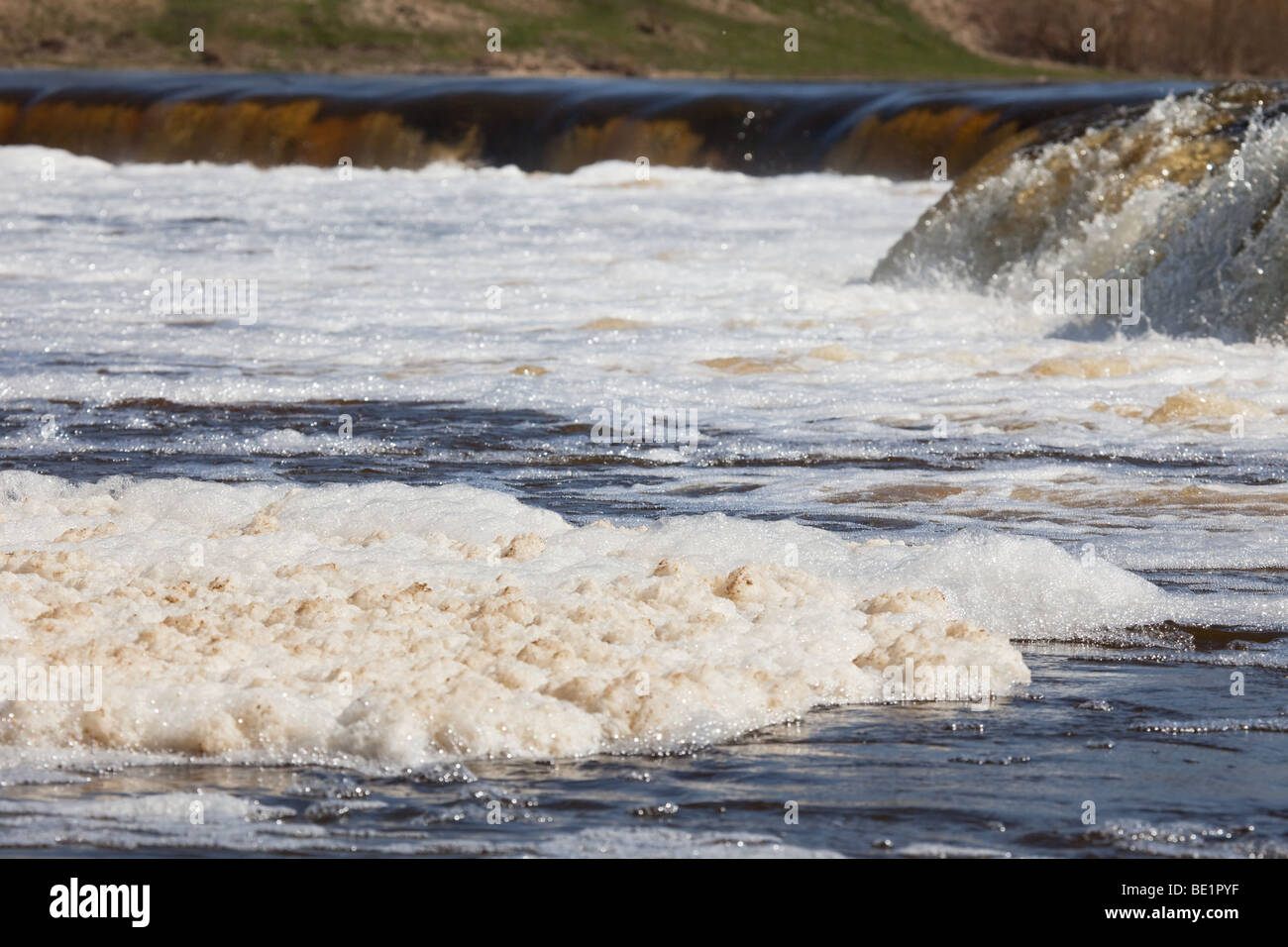 Polluted water foam closeup with waterfall in the background Stock ...