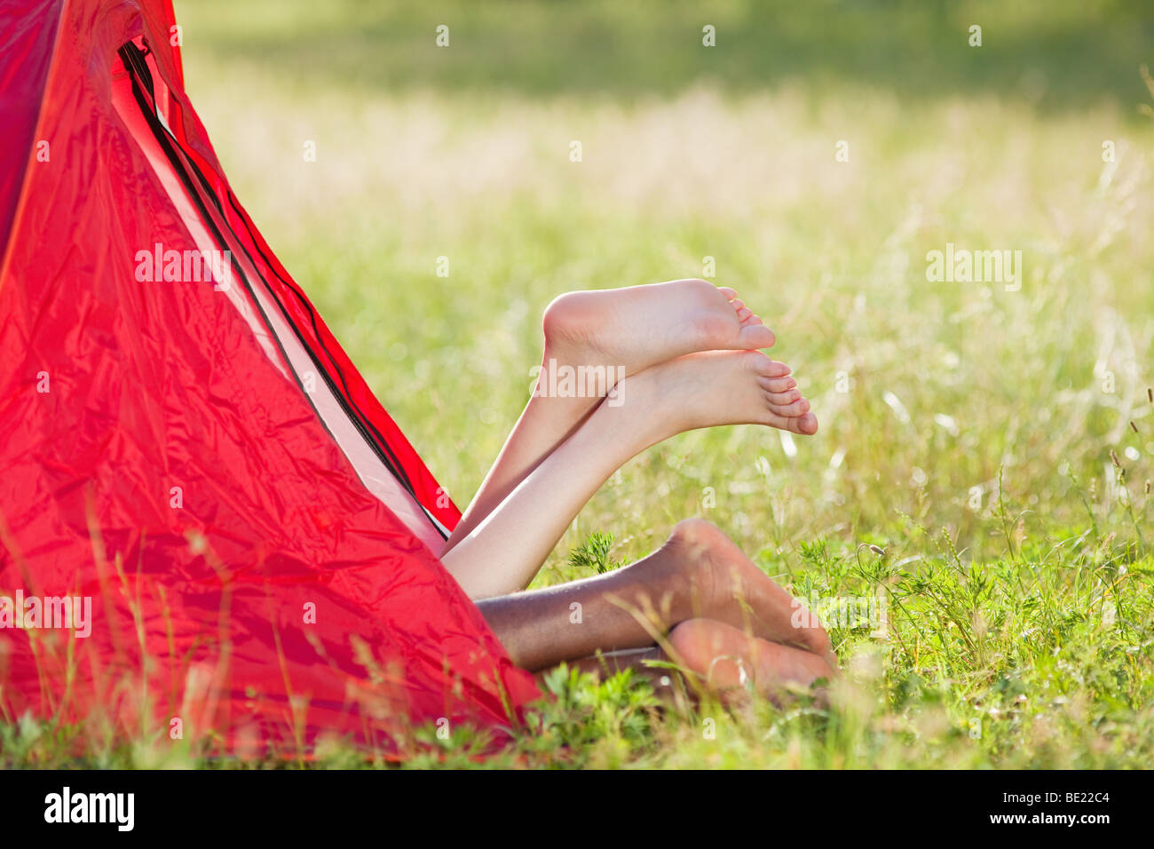 young multiethnic couple lying in tent with feet crossed. Copy space ...