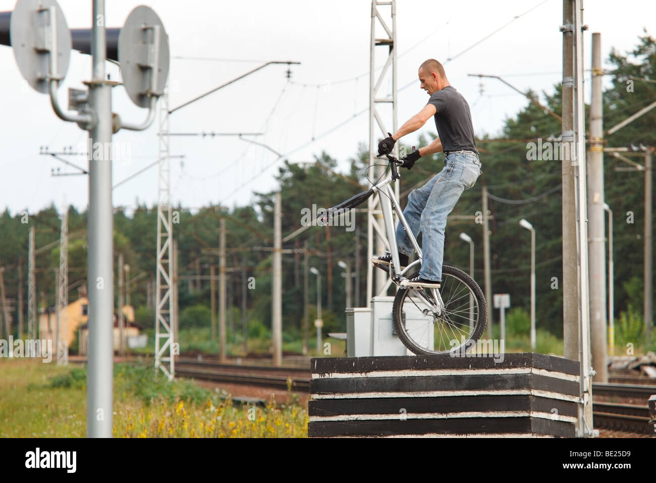Young man standing on concrete blocks without front wheel in urban area ...