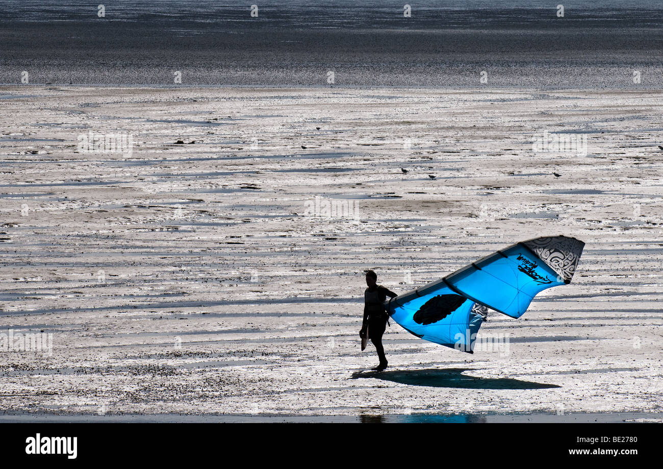 A parasurfer carrying his parasail on the foreshore at East Beach in ...