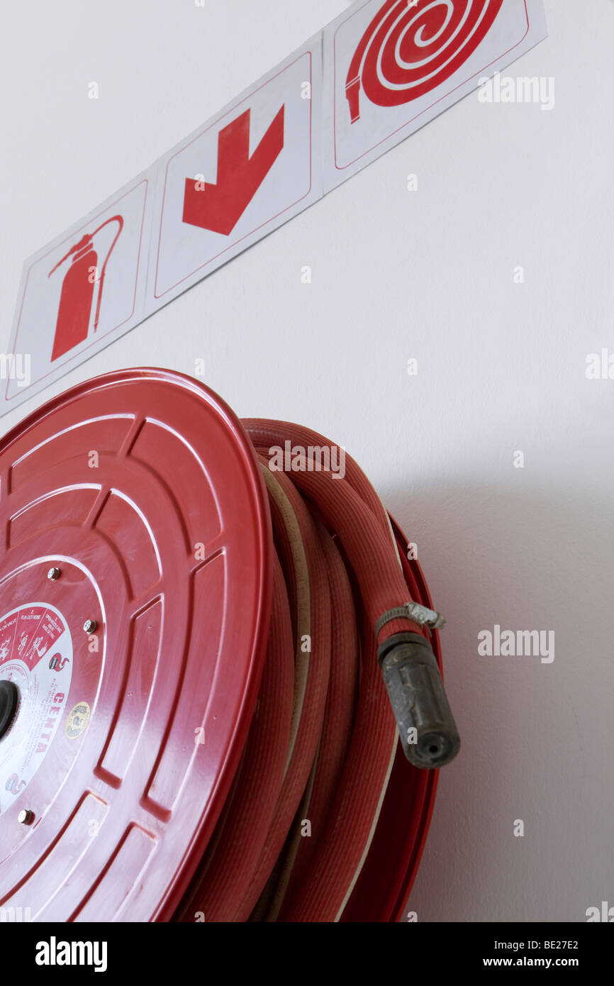 Wall mounted emergency fire fighting hose and safety signs Stock Photo ...