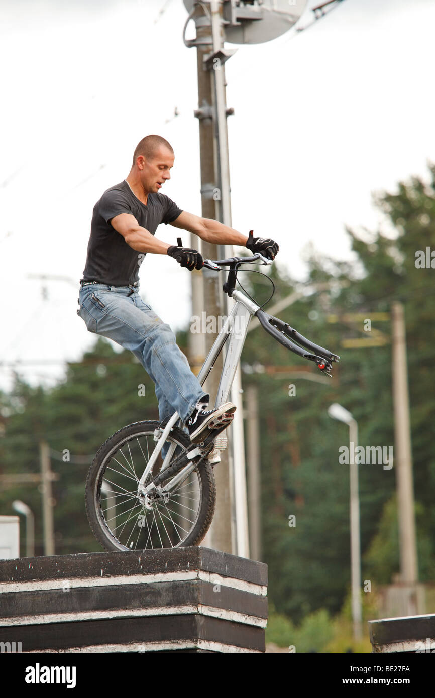 Young man standing on concrete blocks without front wheel in urban area ...