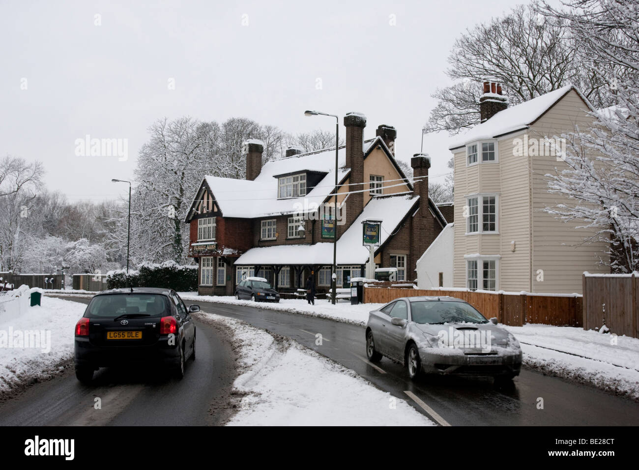 Heavy snow over pub and road in Morden surrey with two cars passing ...