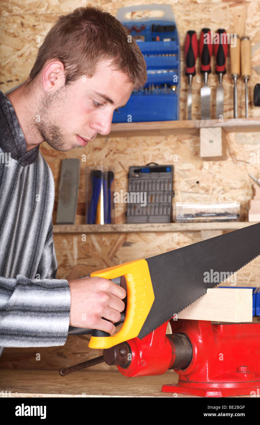 Side view of carpenter cutting wood with saw Stock Photo - Alamy