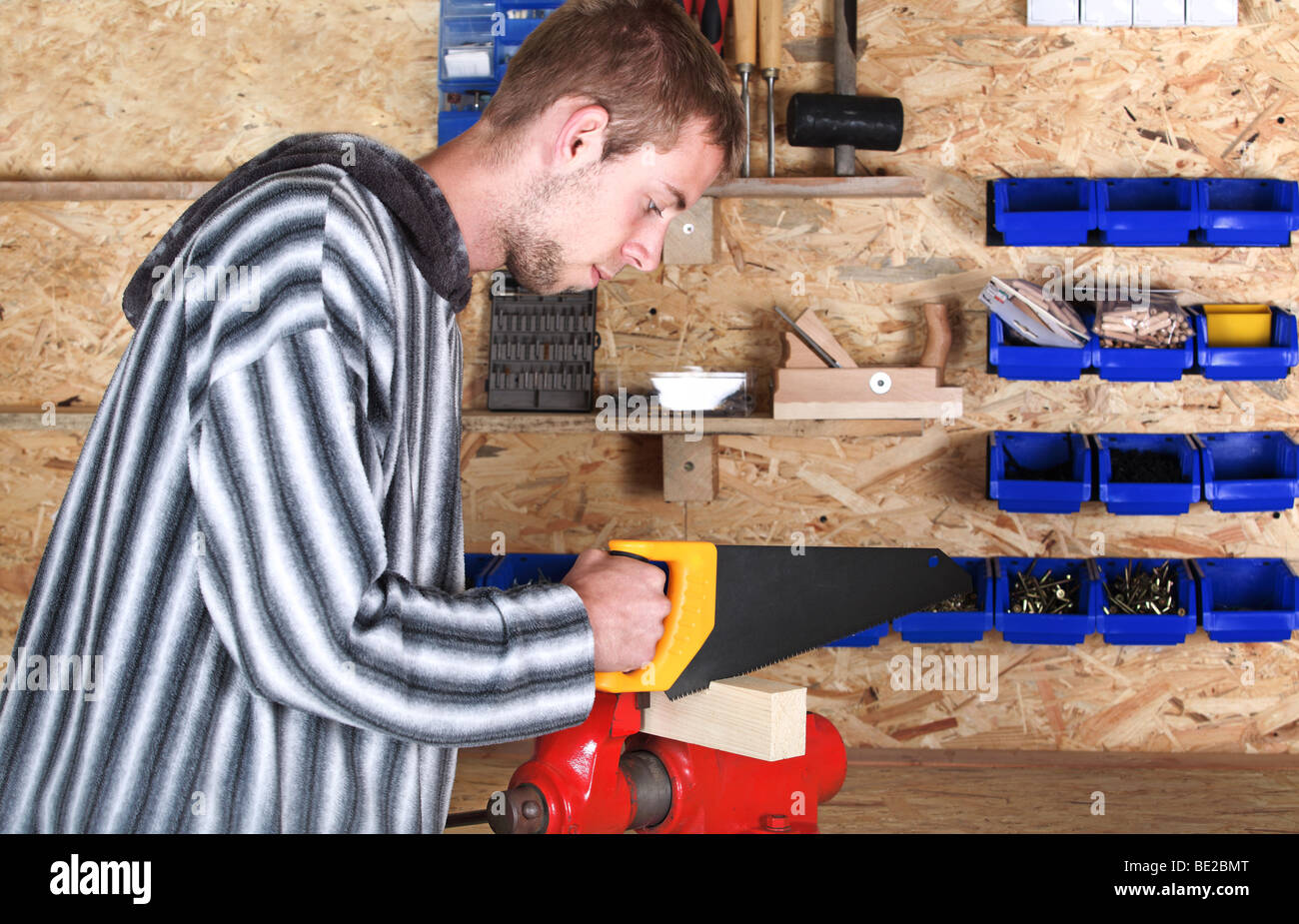 Side view of carpenter cutting wood with saw Stock Photo - Alamy