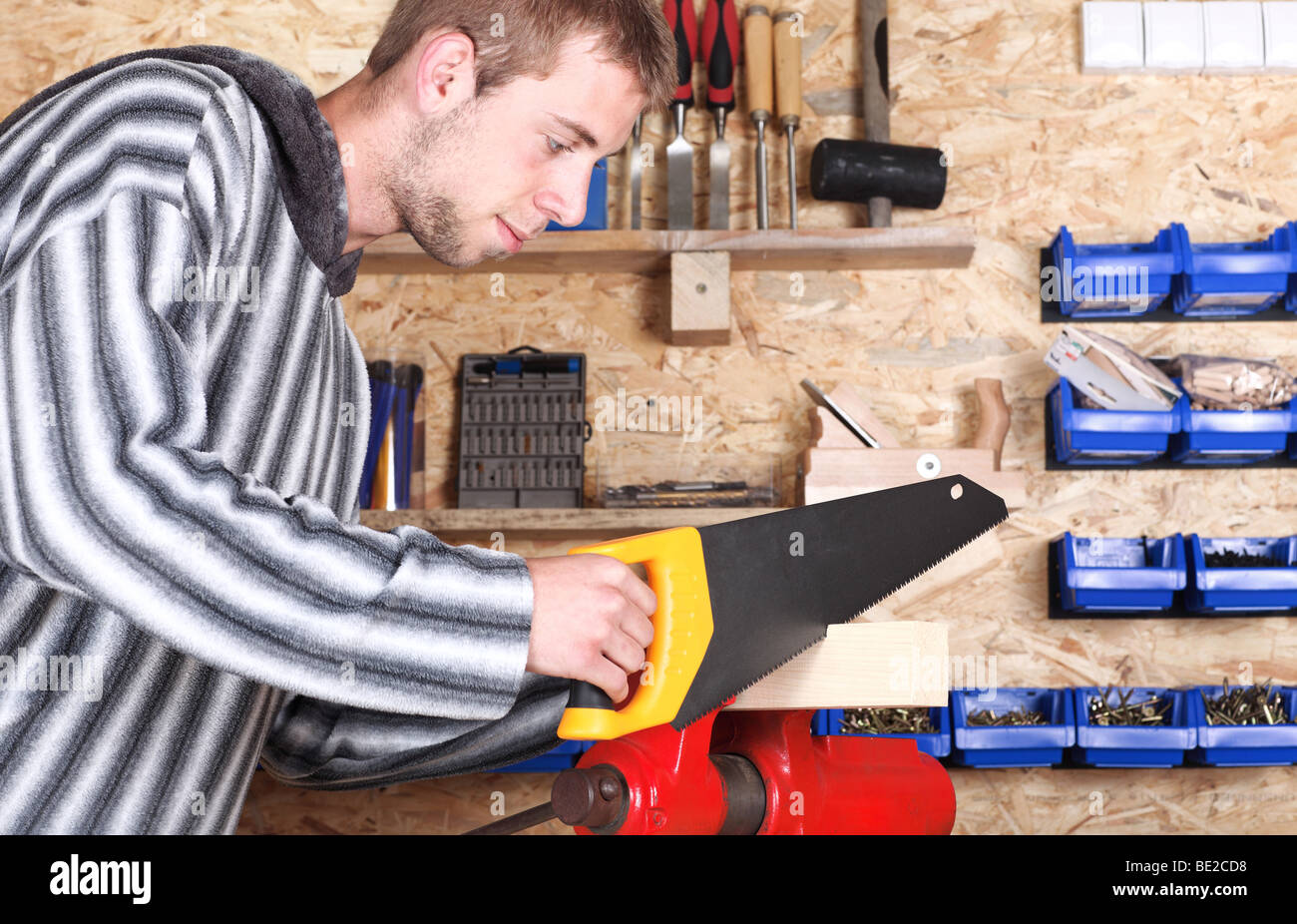Side view of carpenter cutting wood with saw Stock Photo - Alamy