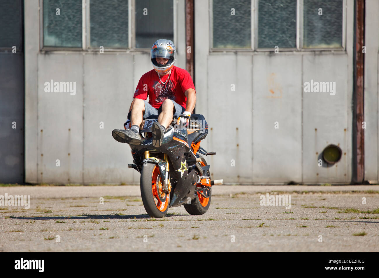 Stunt rider riding bike while keeping his legs over handlebar Stock ...
