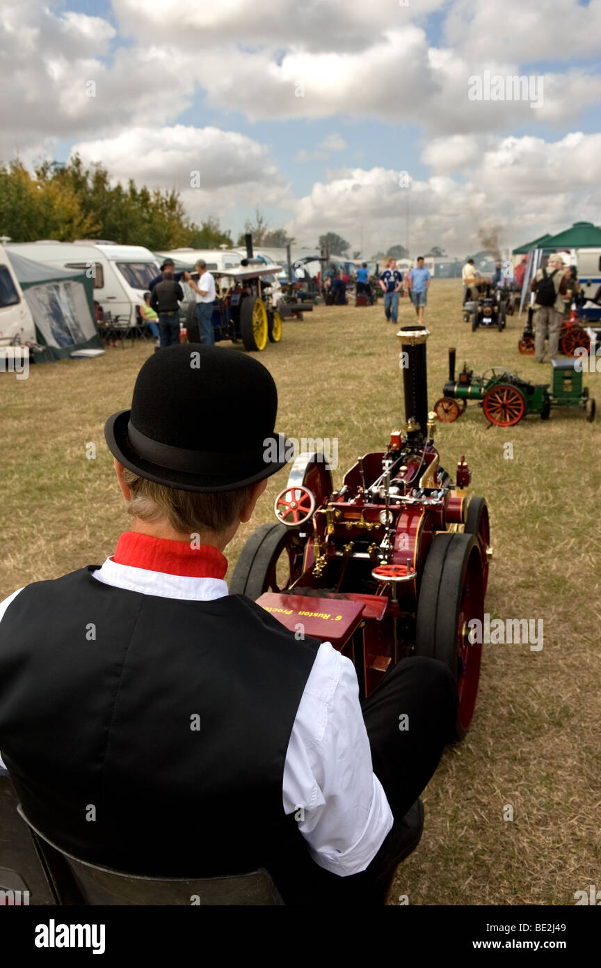 The owner of a miniature steam traction engine sitting on its driving ...
