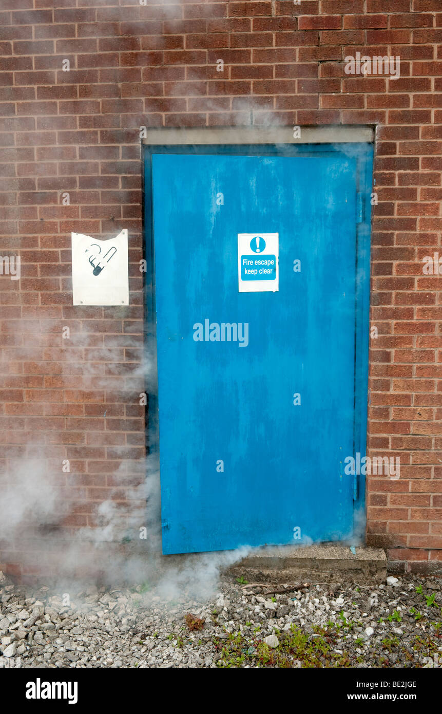 Smoke coming from fire exit door at factory Stock Photo - Alamy