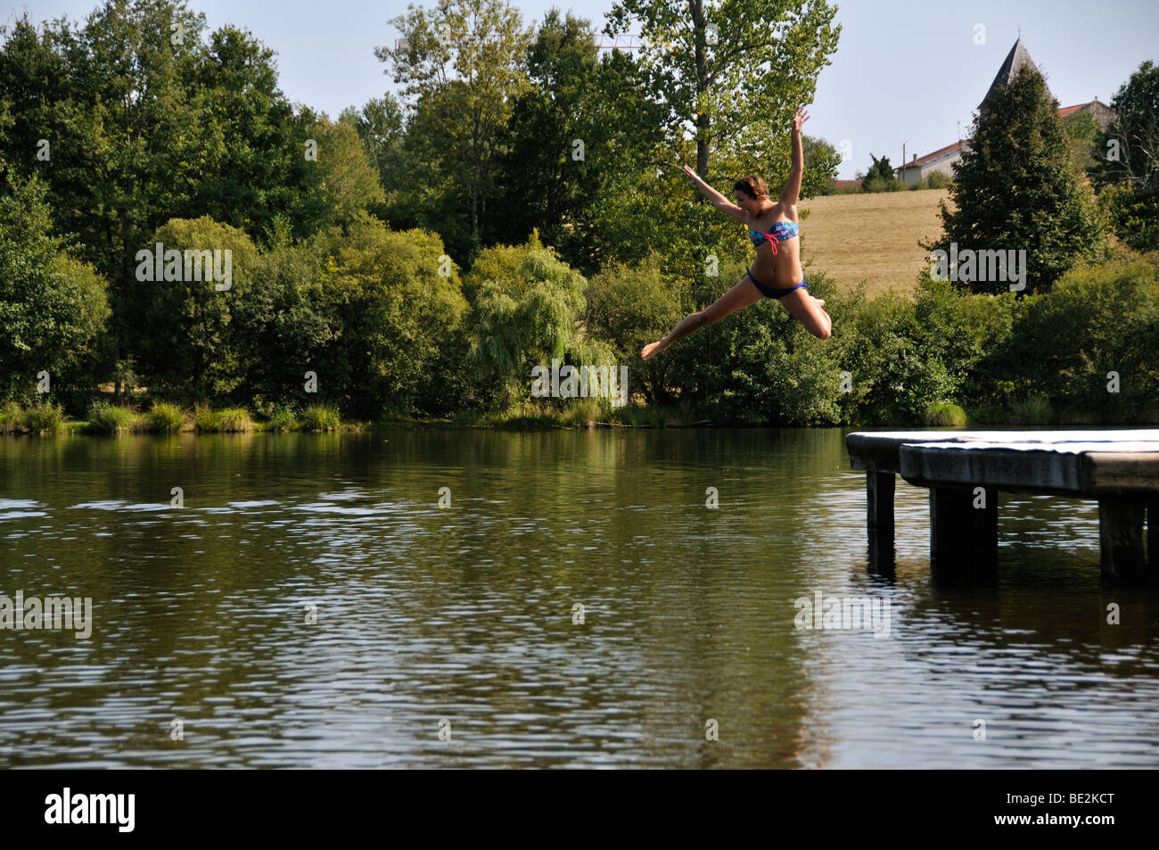 Stock photo of a teenage girl jumping off a pier into a lake Stock ...
