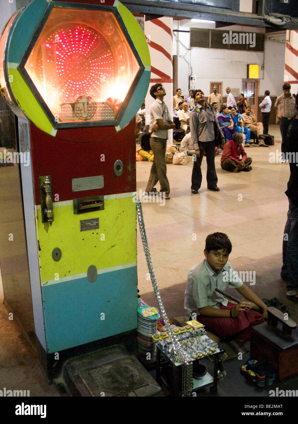Shoe shine boy alongside illuminated machine (thought to be weighing ...
