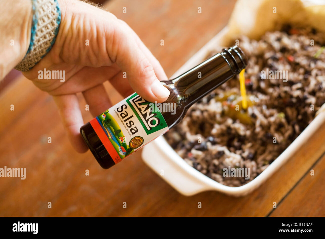 Lizano sauce being poured onto a plate of Gallo Pinto, a typical and ...