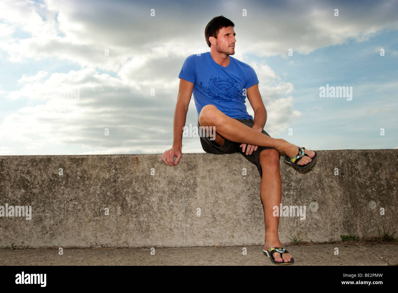 man sitting on a wall relaxing Stock Photo - Alamy