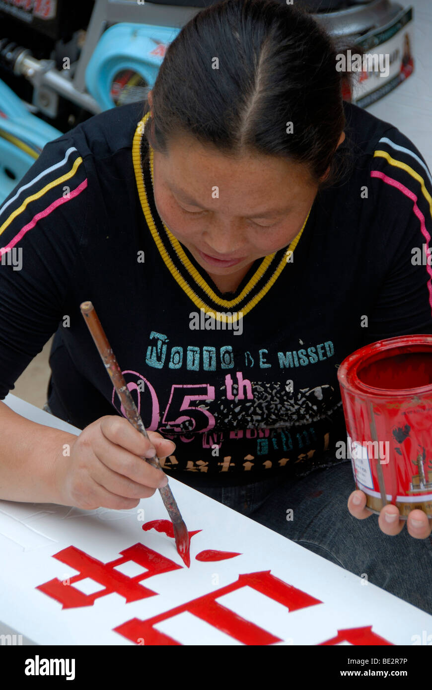Chinese carefully painting Chinese characters with red paint on a sign ...
