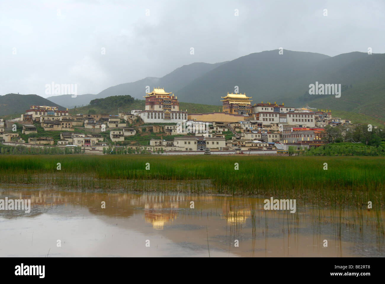 Tibetan Buddhist, monastery reflected in the water, hilly landscape ...