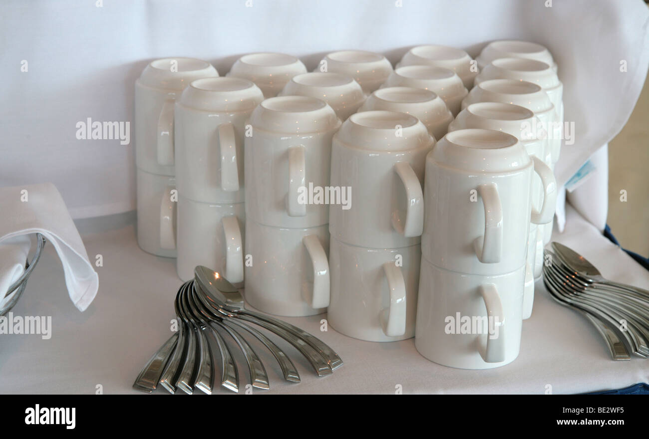 Stack of ceramic coffee mugs and forks for serving a buffet at a hotel ...