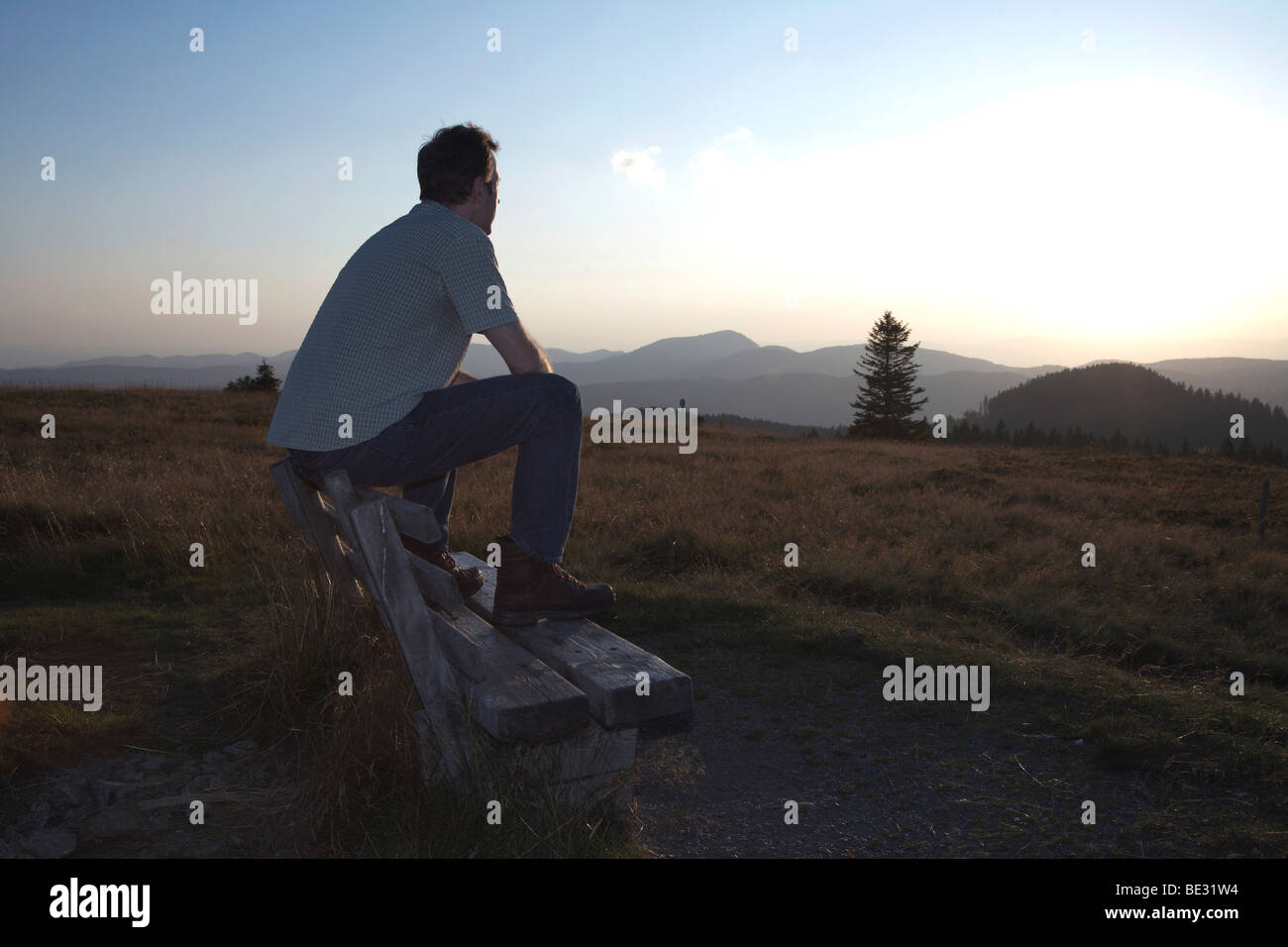 Man, mid 40s, sitting on a bench and looking into the distance, Black ...