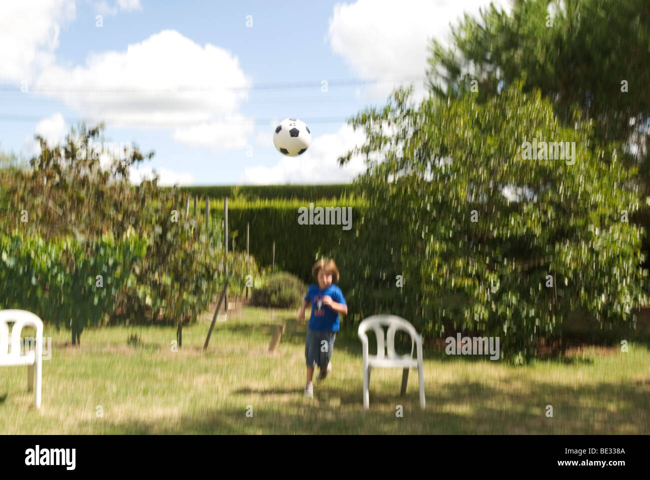 action shot of young boy running towards falling football in private ...