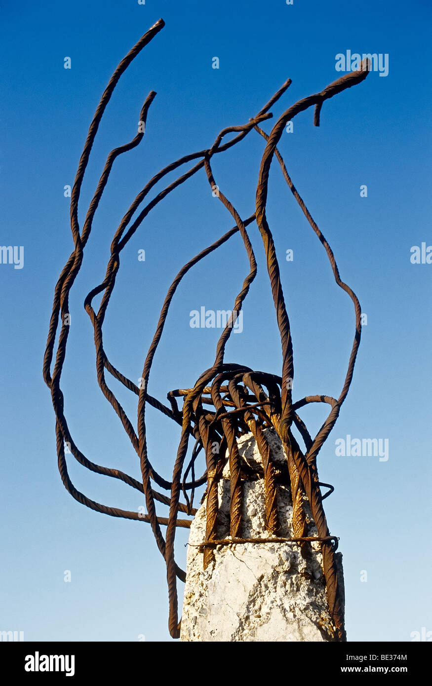 Concrete pylon with rusty, bent reinforcement wires sticking out ...