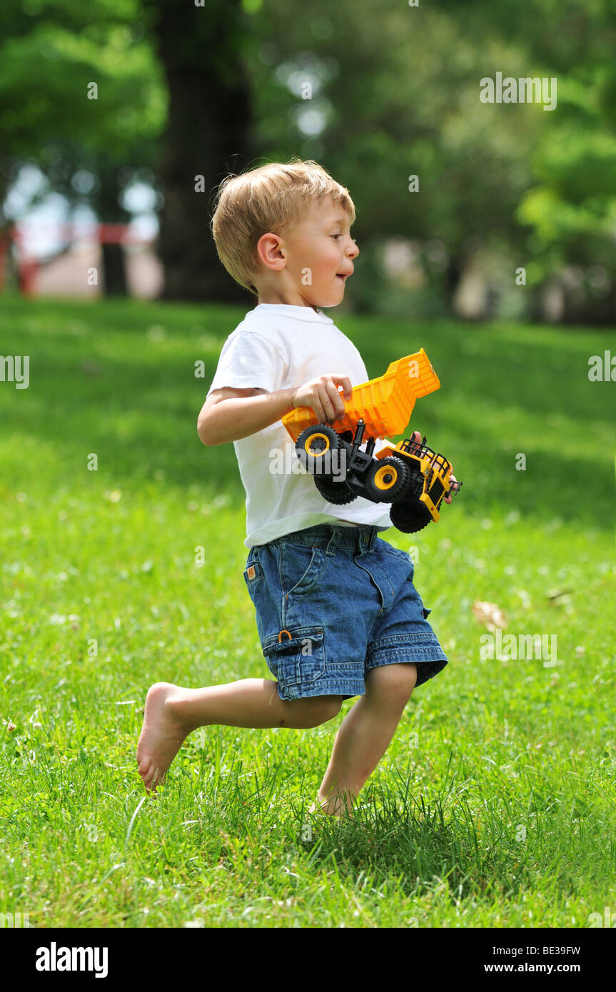 Little boy running with track toy in the park Stock Photo - Alamy