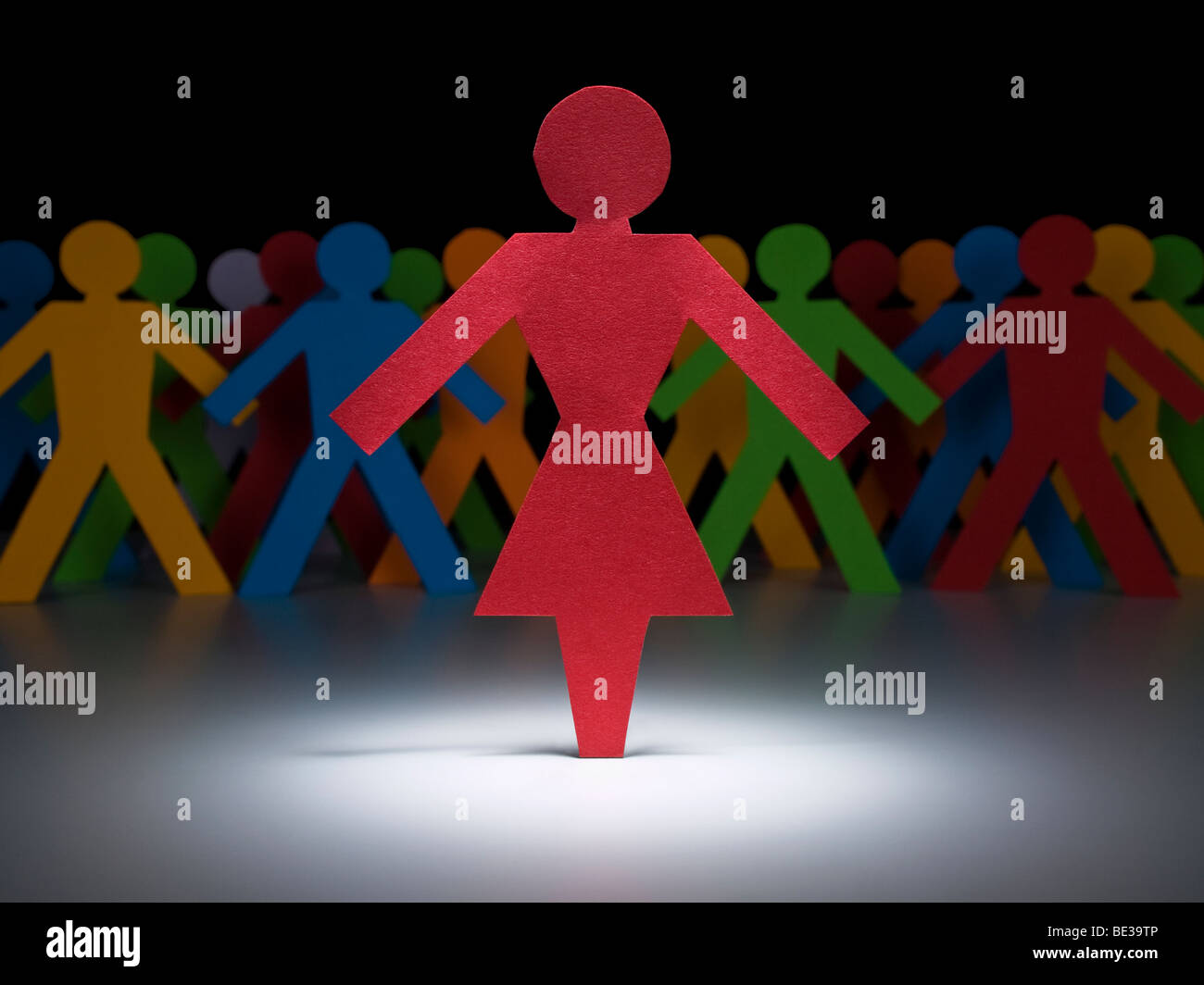 A female paper figure stands under the spotlight in front of multicolor ...