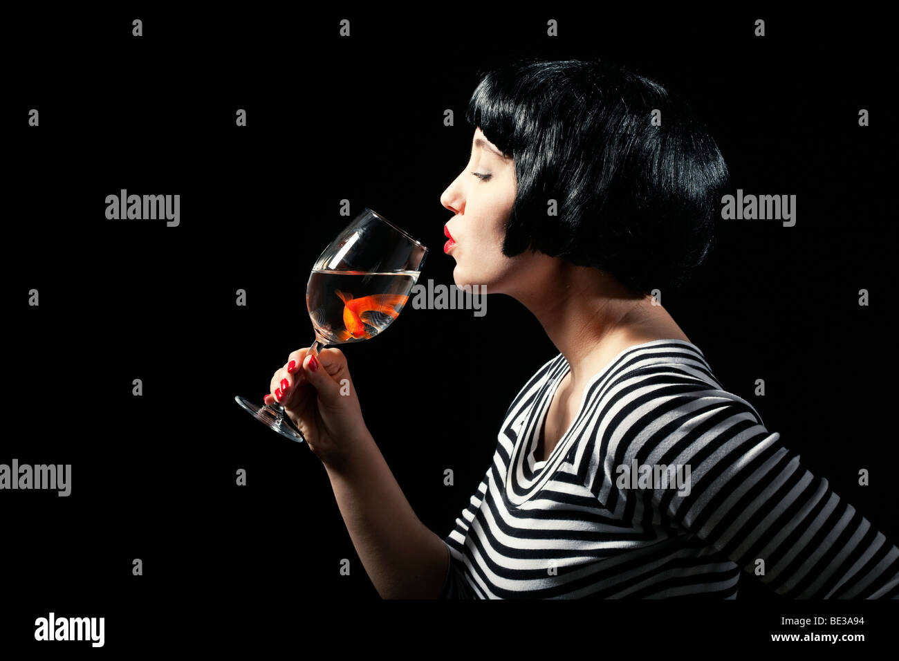 Young woman drinking from a wine glass with a goldfish in it Stock ...