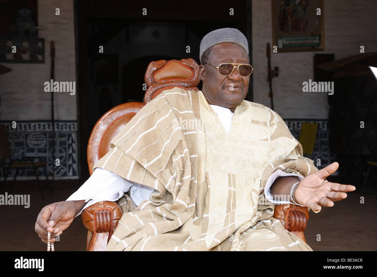 Sultan Ibrahim Mbombo Njoya in front of the Sultan's palace, holding an ...