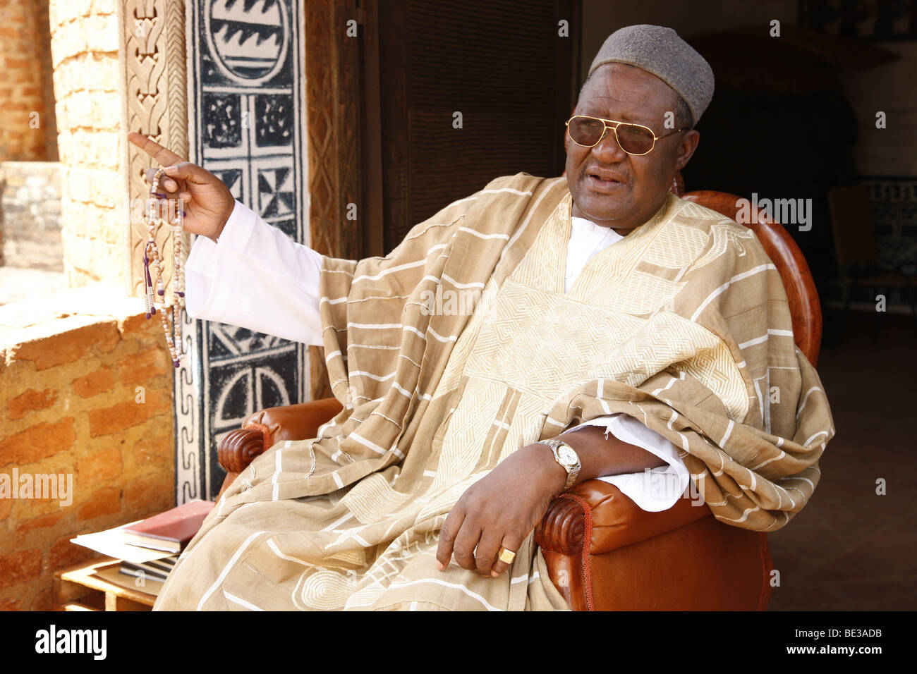 Sultan Ibrahim Mbombo Njoya in front of the Sultan's palace, holding an ...