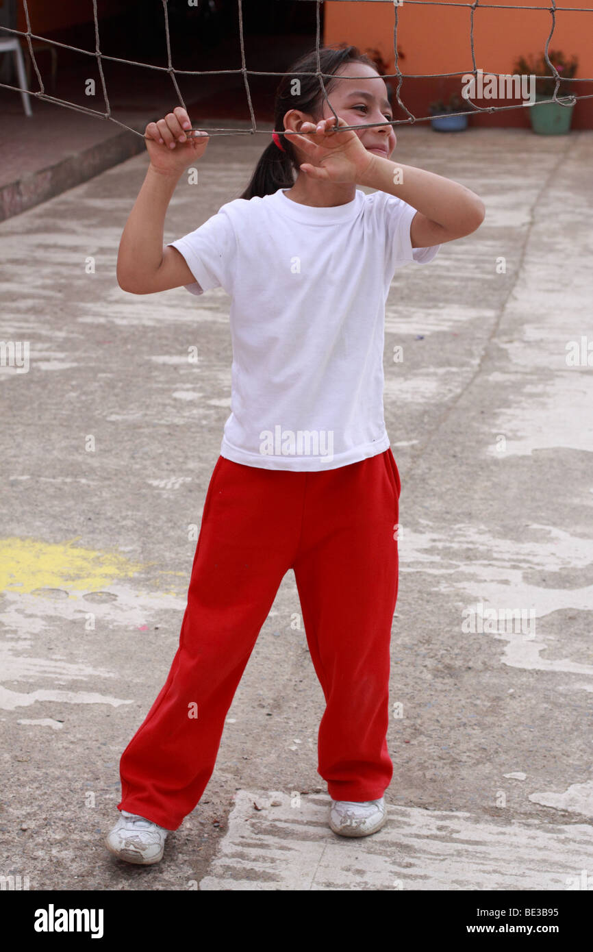 Portrait of a little girl smiling in the schoolyard hanging on a ...