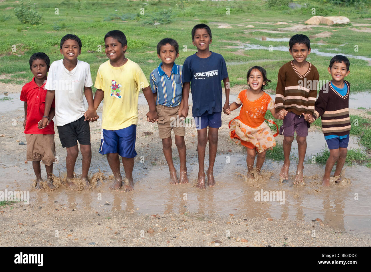 Indian children jumping and splashing in a puddle of water in the ...