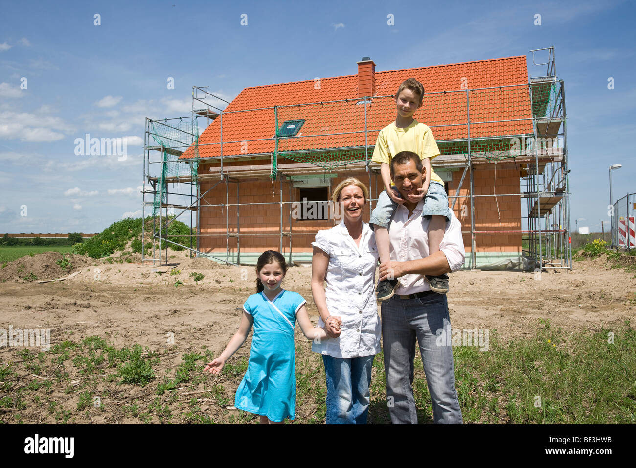 Family standing in front of their future home Stock Photo - Alamy