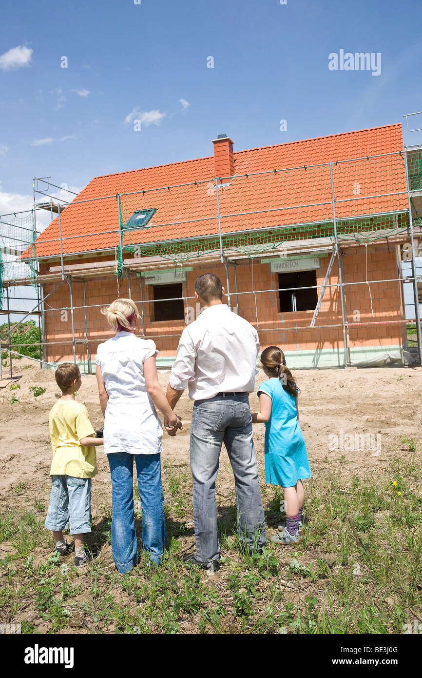 Family standing in front of their future home Stock Photo - Alamy