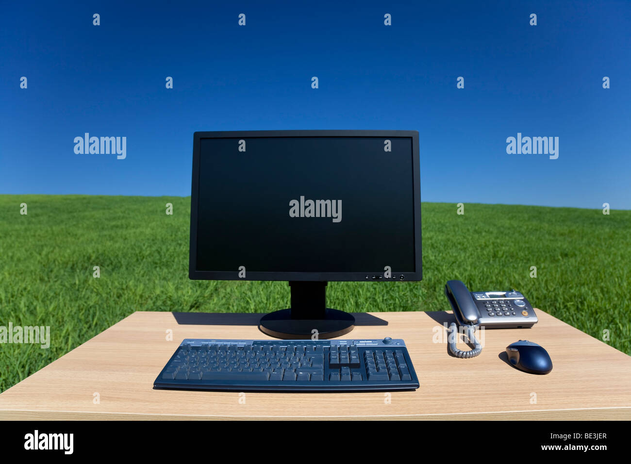 Business concept shot showing a computer on a desk in a green field ...