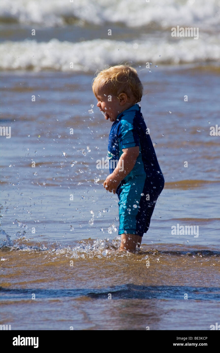 A small boy spits out salt water having been splashed by a wave at the ...